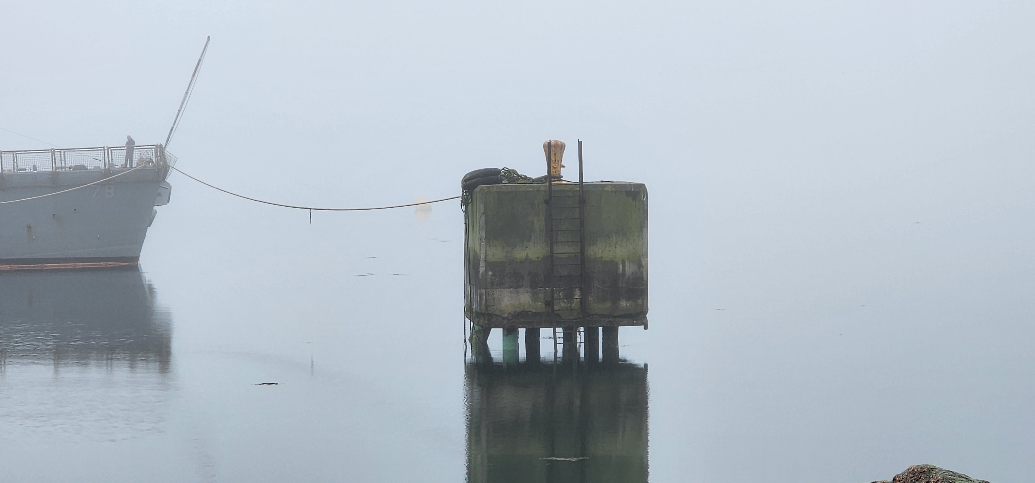 Harbor worker on a mooring dolphin with a ship’s line attached to its ...